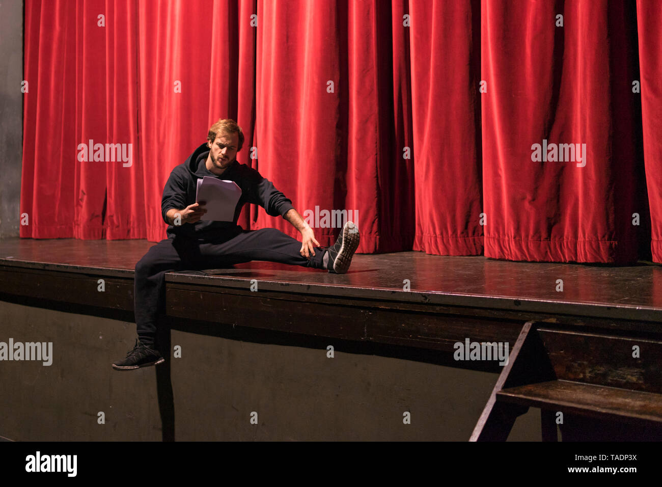 Actor sitting on stage of theatre studying script Stock Photo - Alamy
