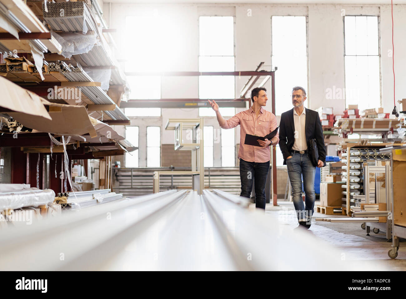 Two men walking in factory warehouse Stock Photo - Alamy