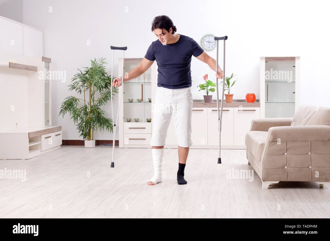 Leg injured young man suffering at home Stock Photo - Alamy