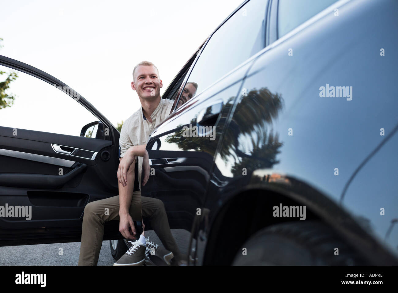 Smiling young man sitting in a car looking around Stock Photo - Alamy