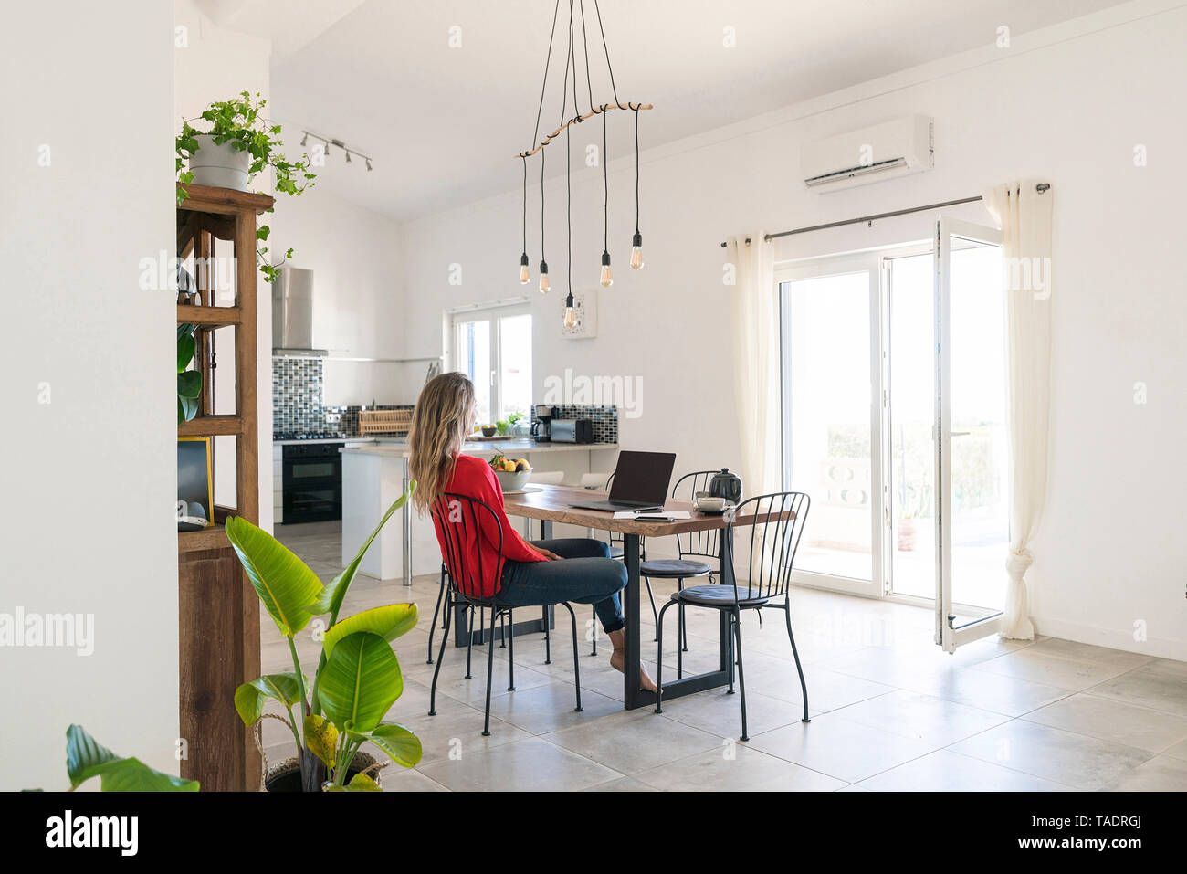 Woman using laptop on dining table in modern home Stock Photo - Alamy