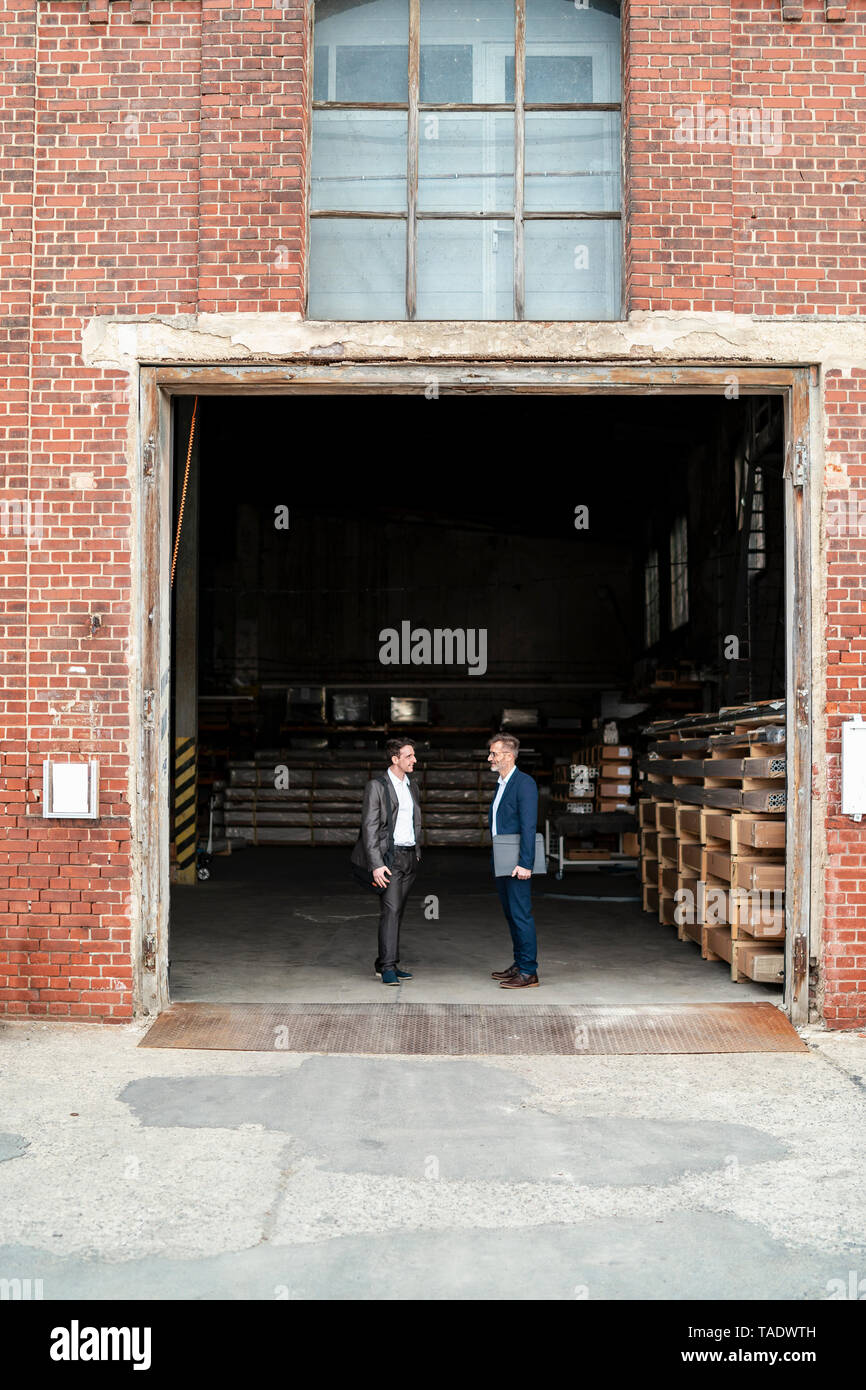 Two businessmen talking at an old storehouse Stock Photo - Alamy