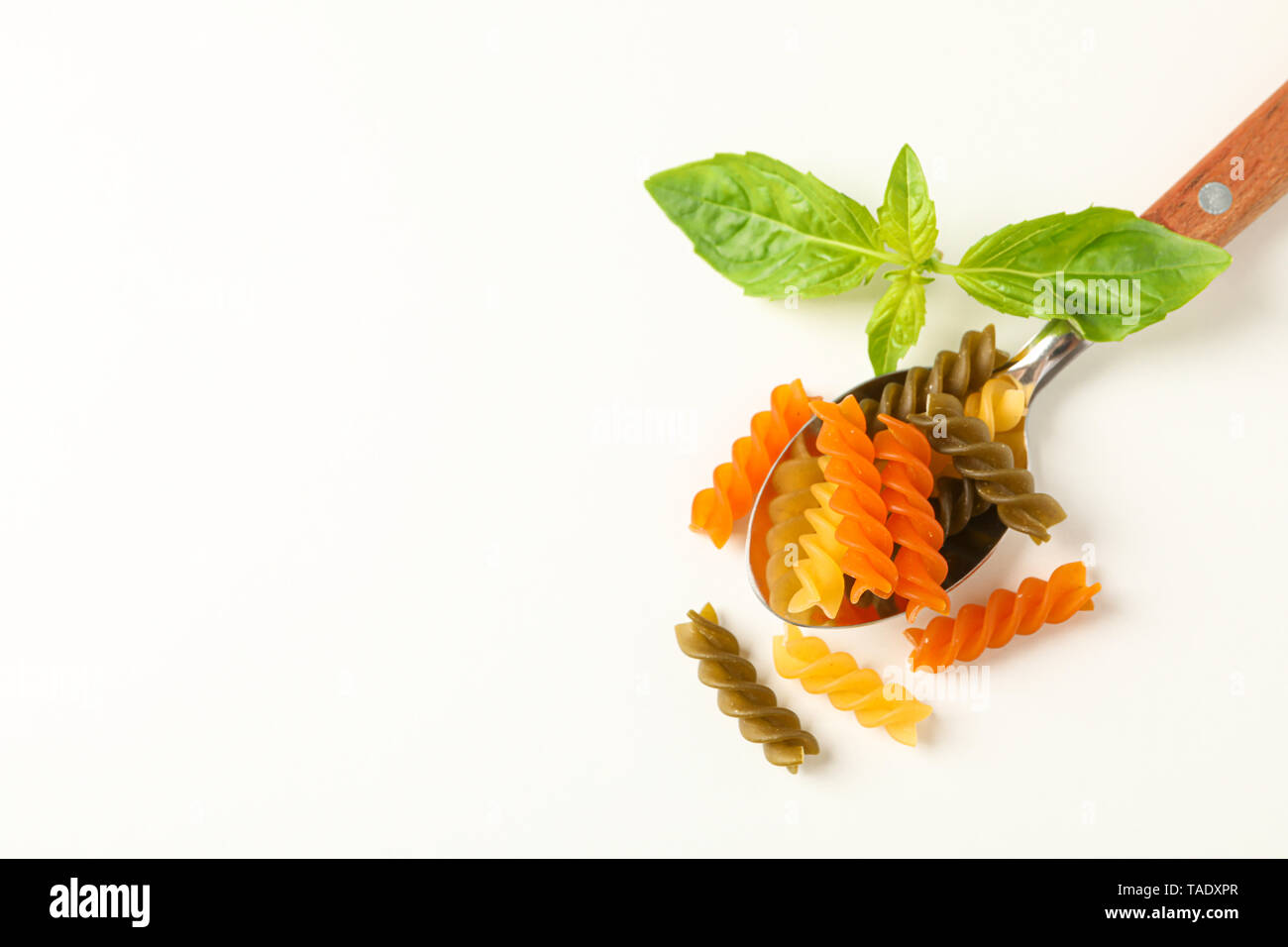 Spoon with color pasta on white background, space for text and top view ...
