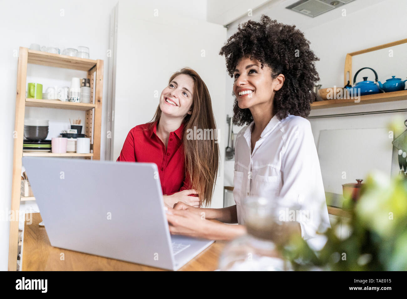 Two women working together in kitchen, using laptop Stock Photo - Alamy