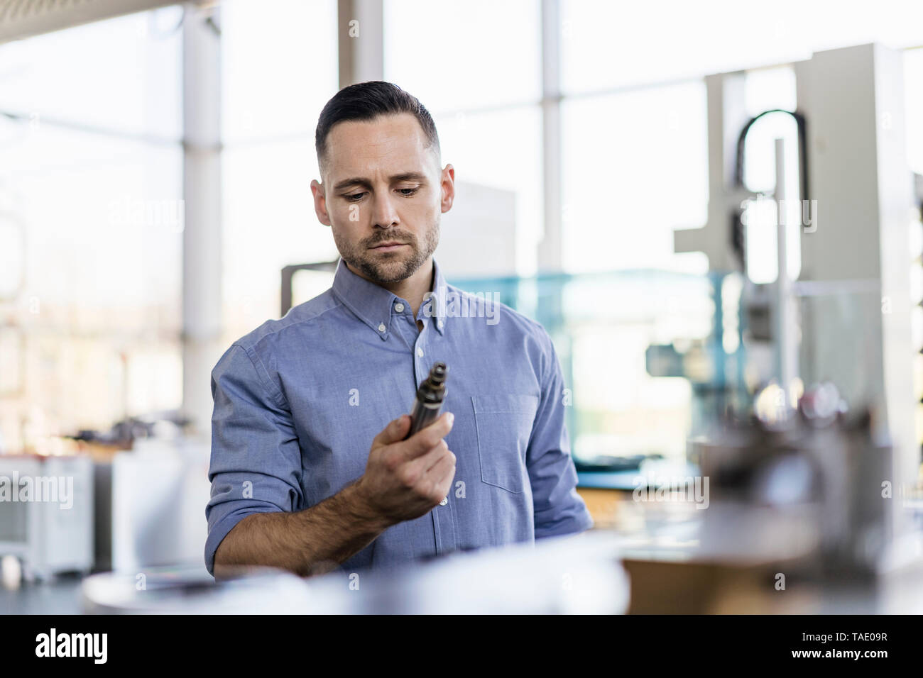 Businessman examining workpiece in factory Stock Photo - Alamy