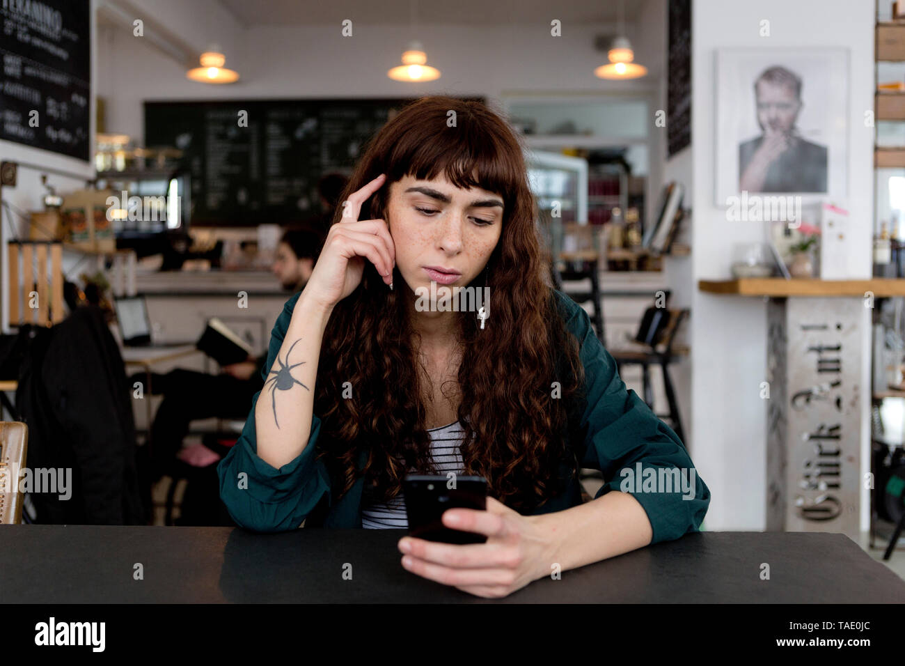 Young woman using cell phone in a cafe Stock Photo - Alamy