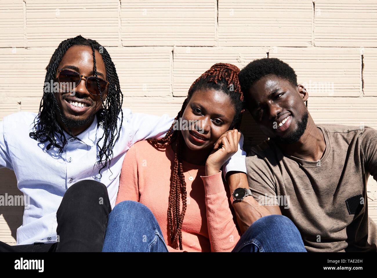 Portrait of three smiling friends at a wall Stock Photo - Alamy