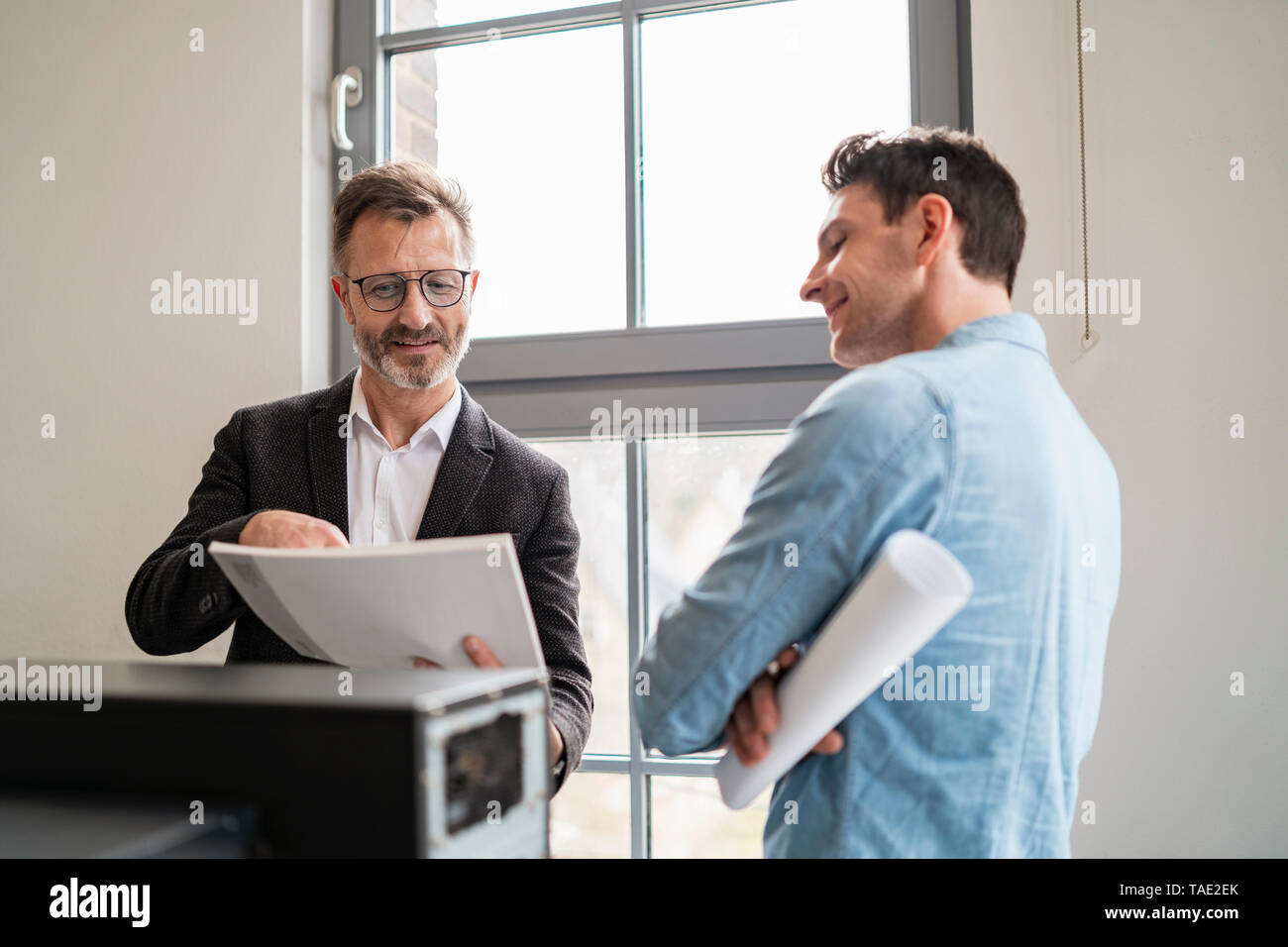Two colleagues talking at the window in office Stock Photo - Alamy