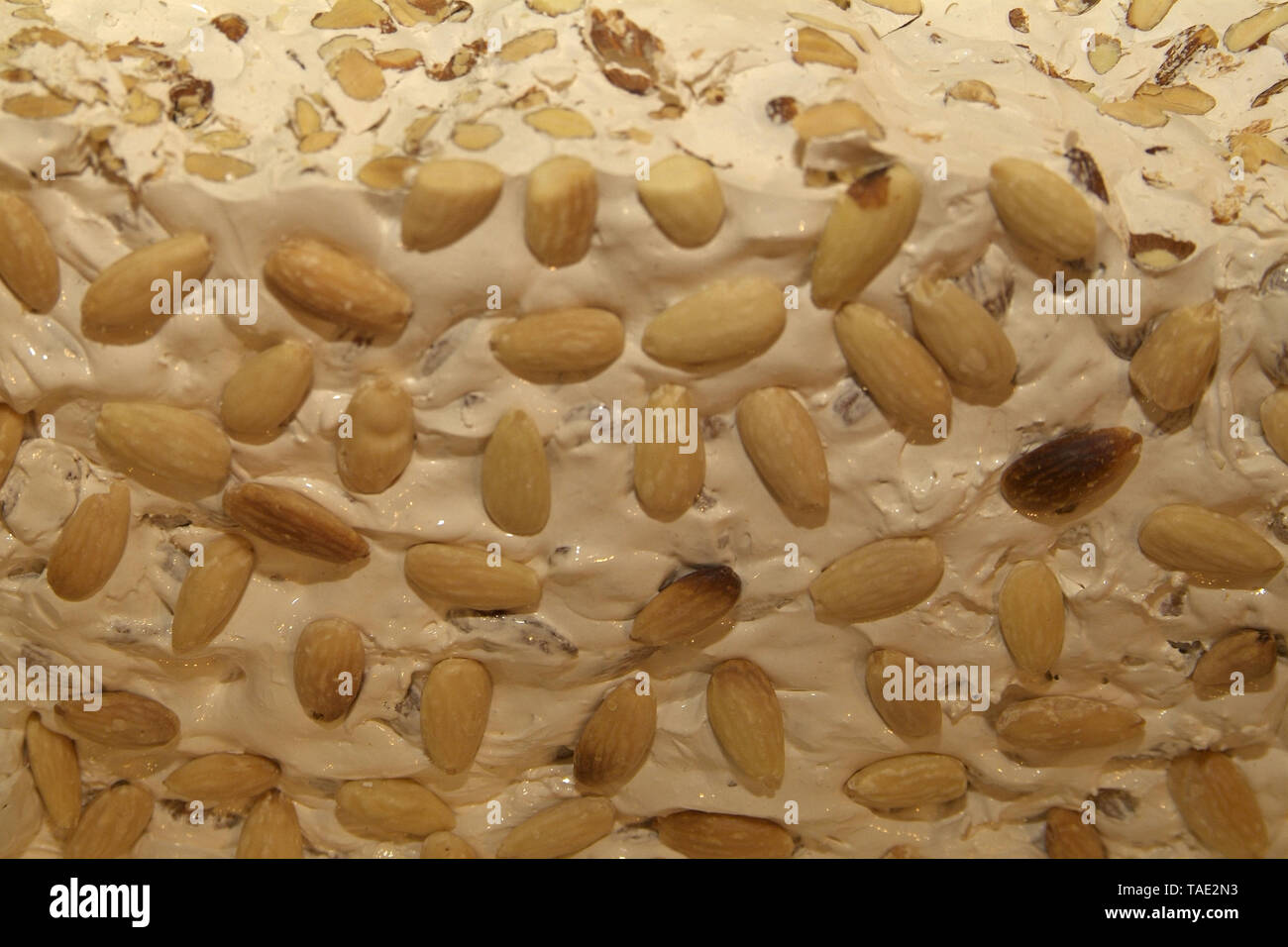Italian torrone or nougat with almonds on a white wooden table, close ...