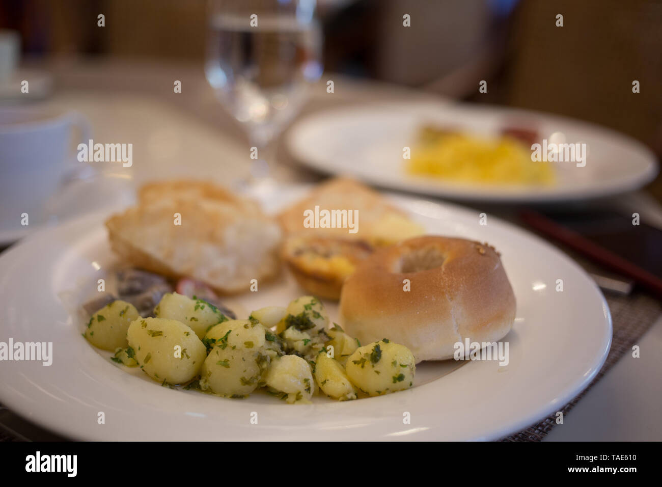 A plate with a simple hotel breakfast consisting of potatoes and bread ...