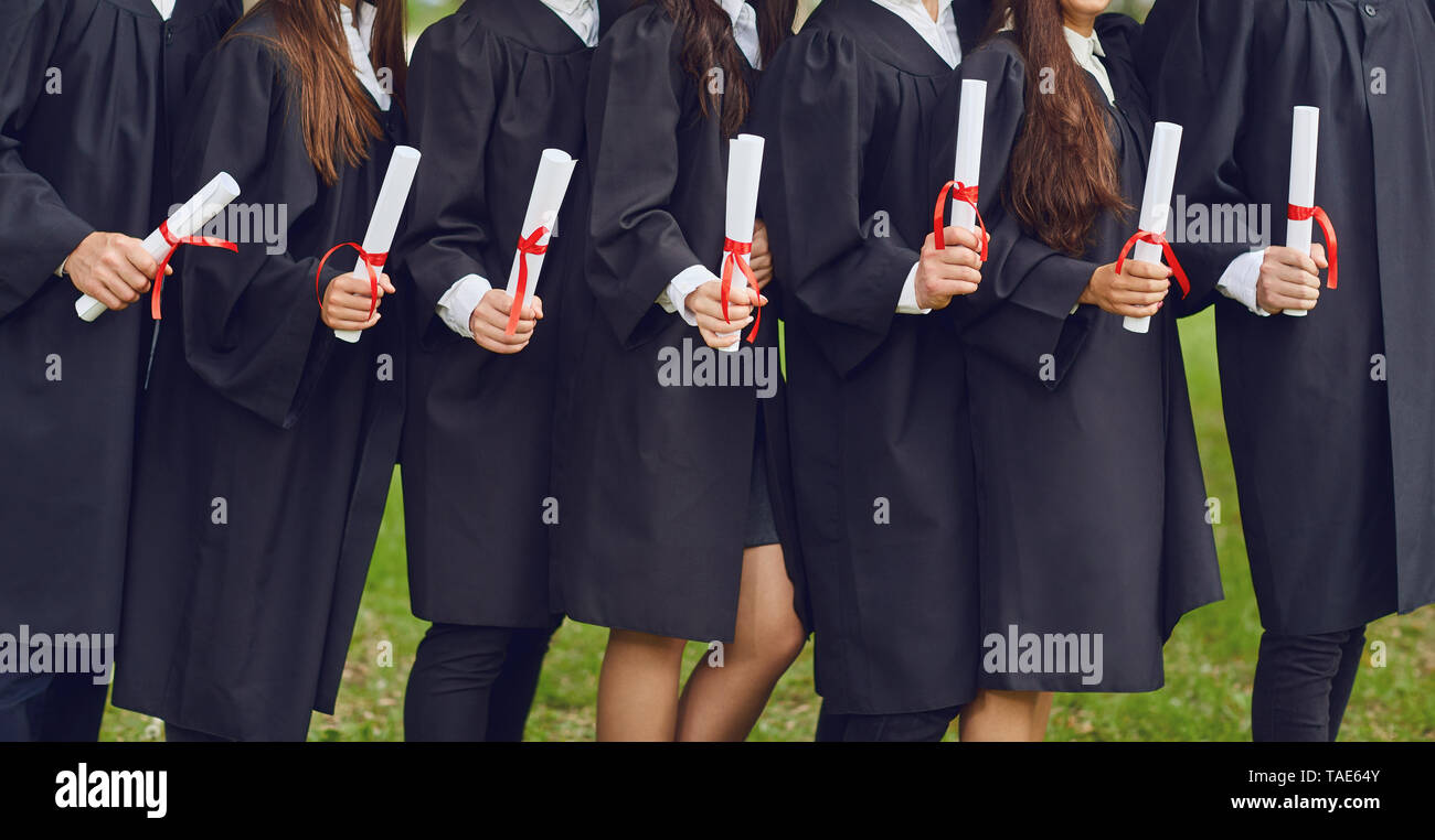 Scrolls of diplomas in the hands of a group of graduates. Graduation ...