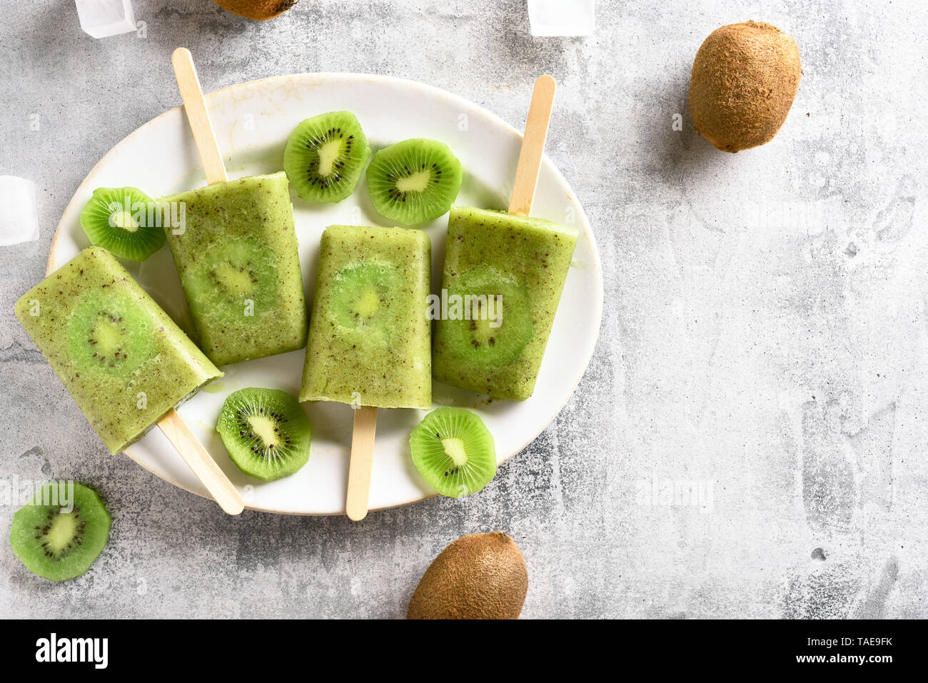 Popsicles from kiwi on plate over stone background with copy space. Top ...