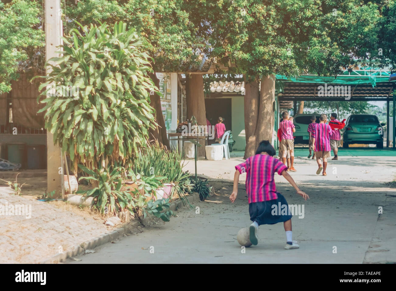 Back view of Girl student wear skirt to practice playing football alone ...