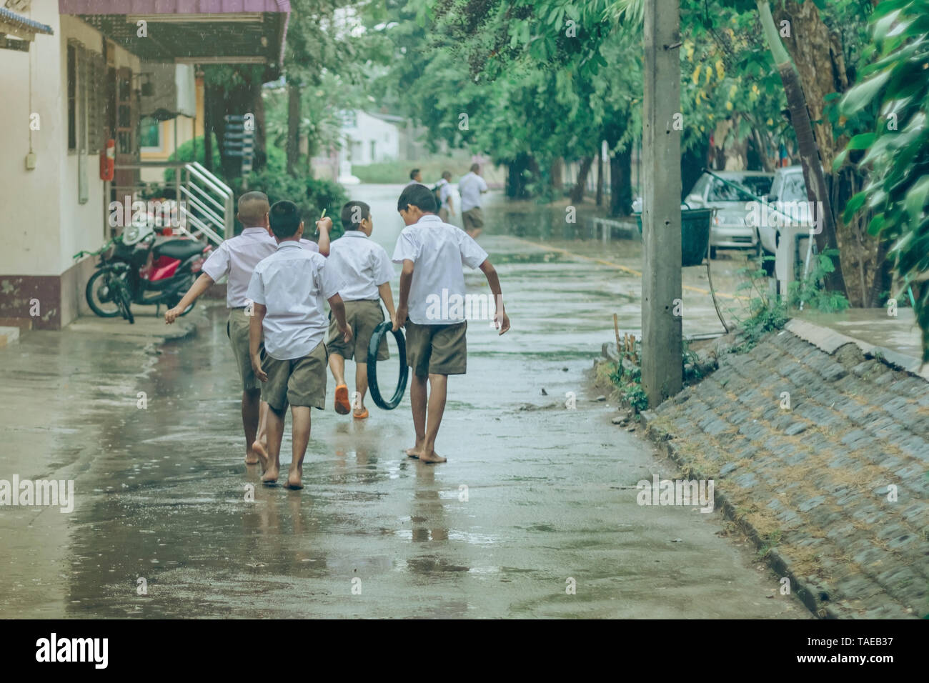 Boy students leave the classroom to walk on the street after heavy rain ...
