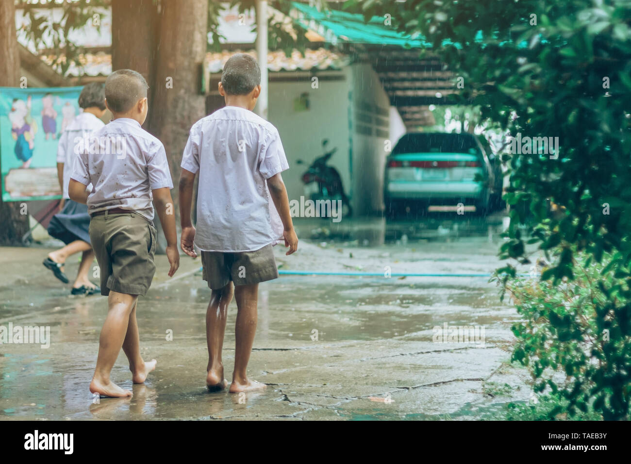 Boy students leave the classroom to walk on the street after heavy rain ...