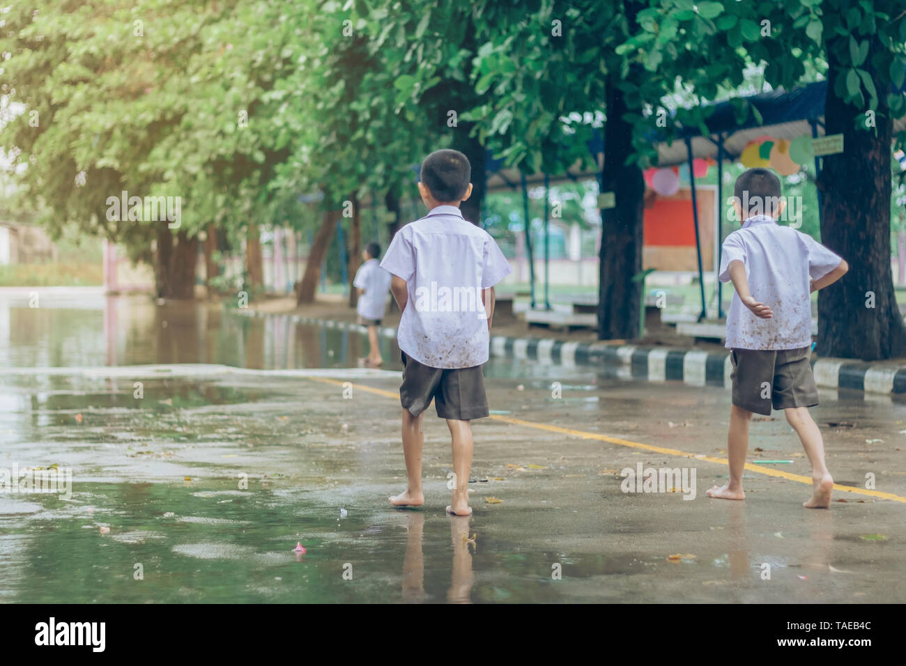 Boy students leave the classroom to walk on the street after heavy rain ...