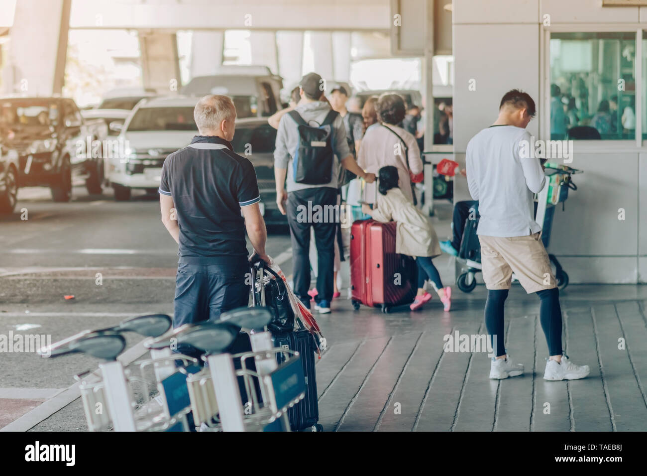 Passengers with big roller luggage stand to wait for the car to pick up ...