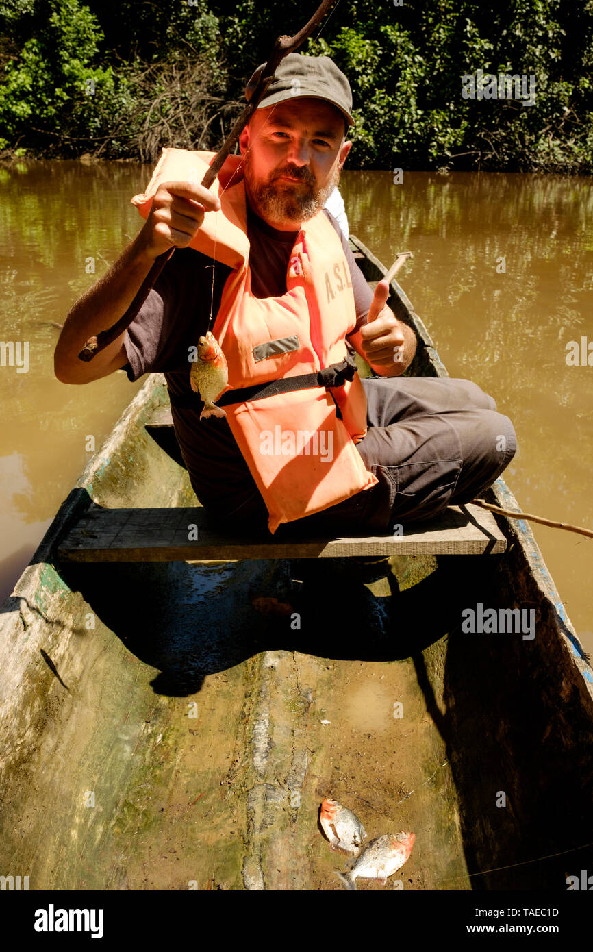 White tourist man on a small wooden boat fishing the piranha on ...