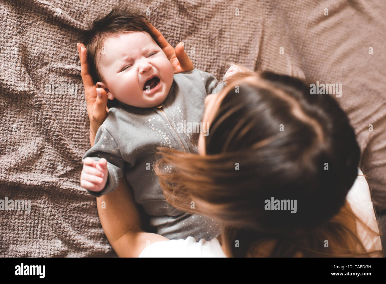 Mother try calm her crying baby in bed. Maternity. Motehrhood Stock ...