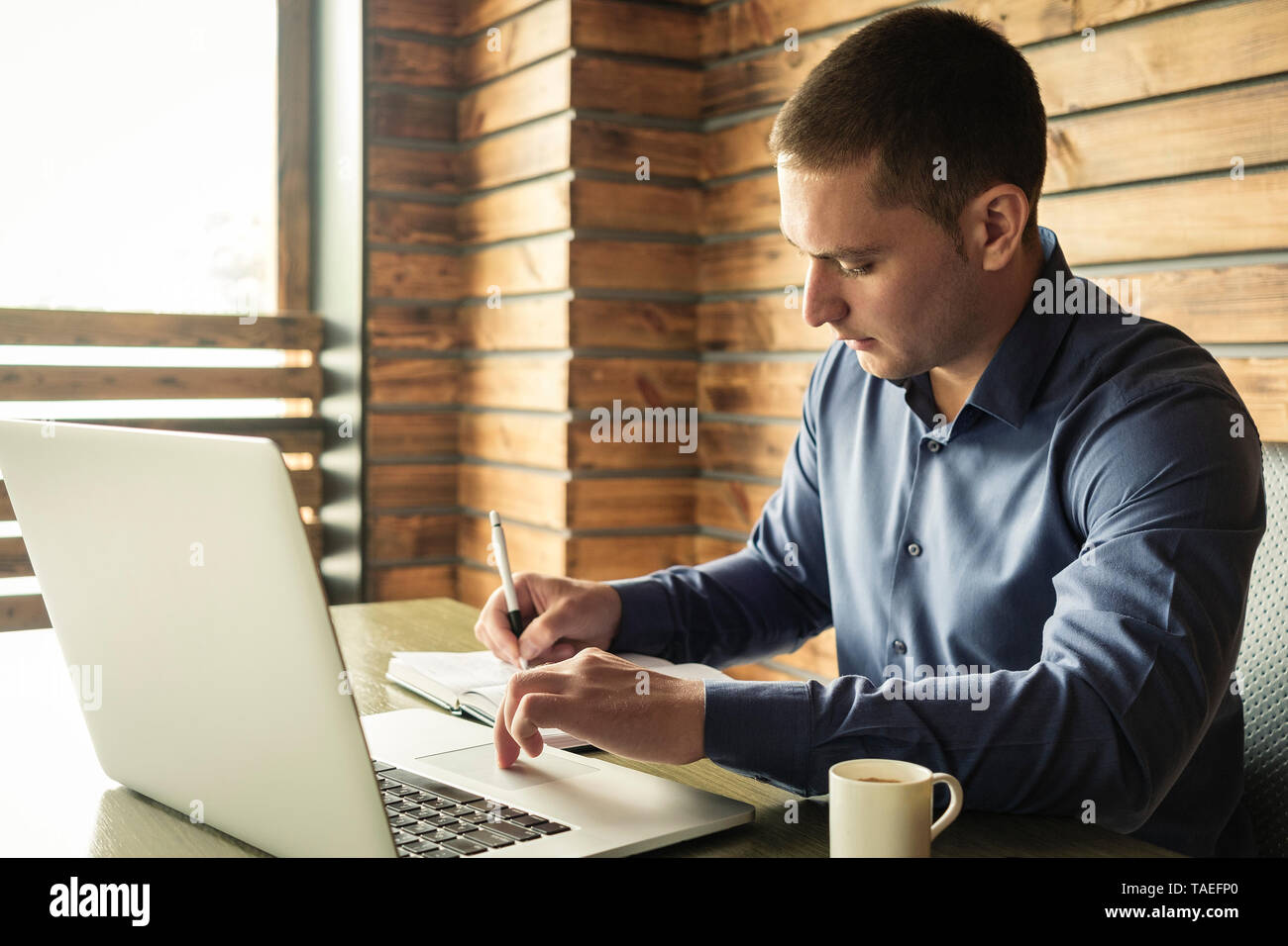 Young businessman taking notes from his laptop computer reading the ...