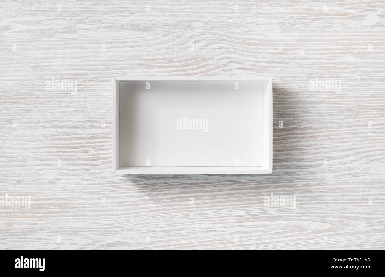 Blank white opened box on light wood table background. Responsive ...