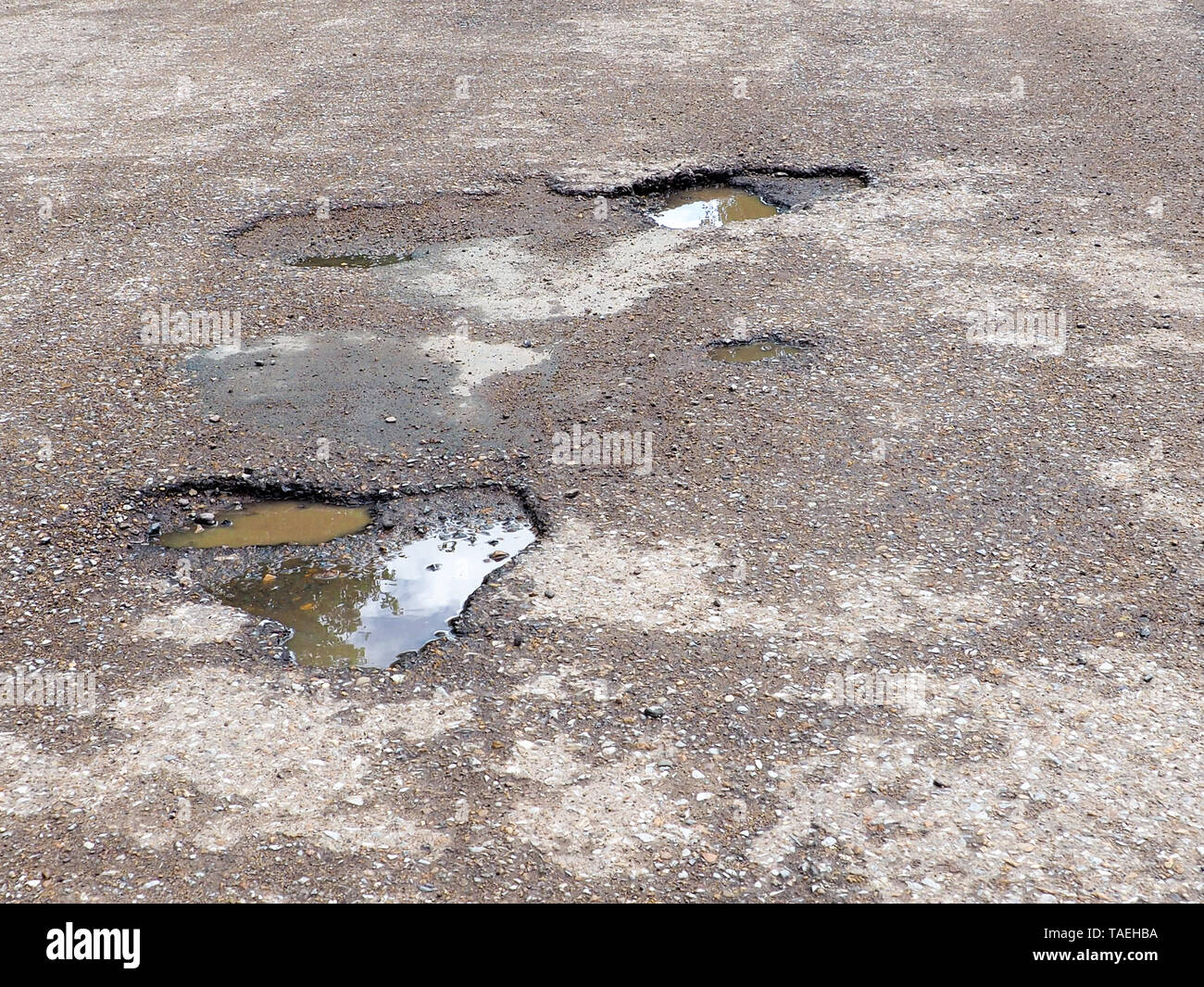 large pits with stones on the asphalt road Stock Photo - Alamy