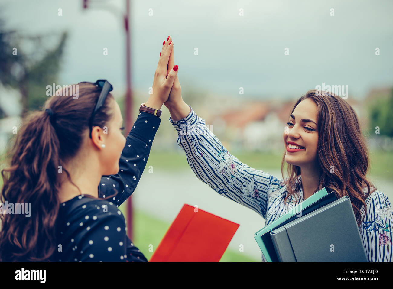 Two happy female students are giving high five after successfully ...