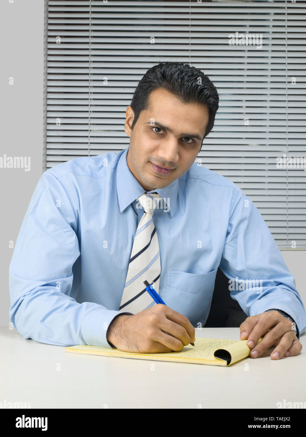 CORPORATE EXECUTIVE writing notes while working on his desk Stock Photo ...