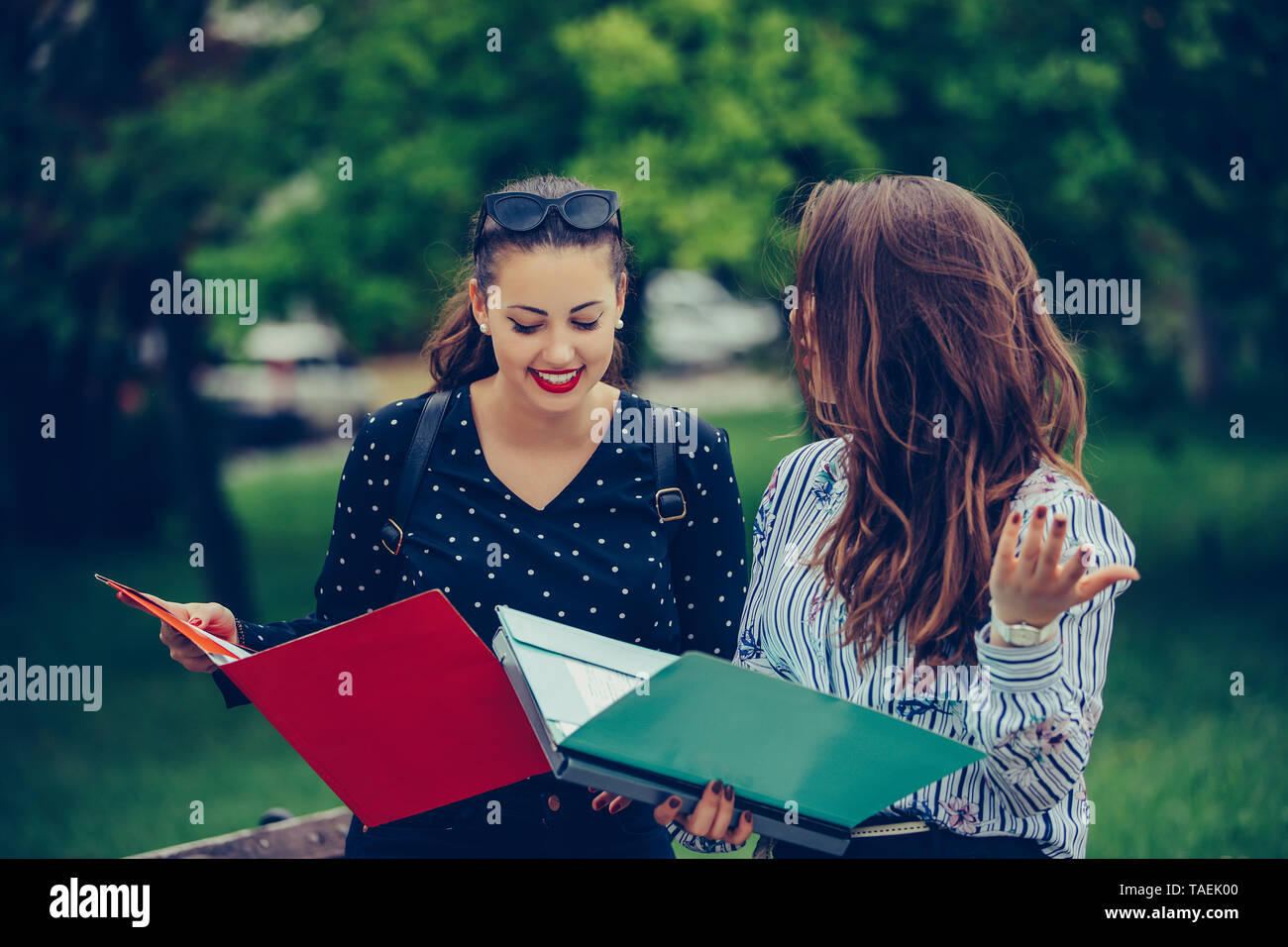 Two beautiful female friends, students checking paper notes before exam ...