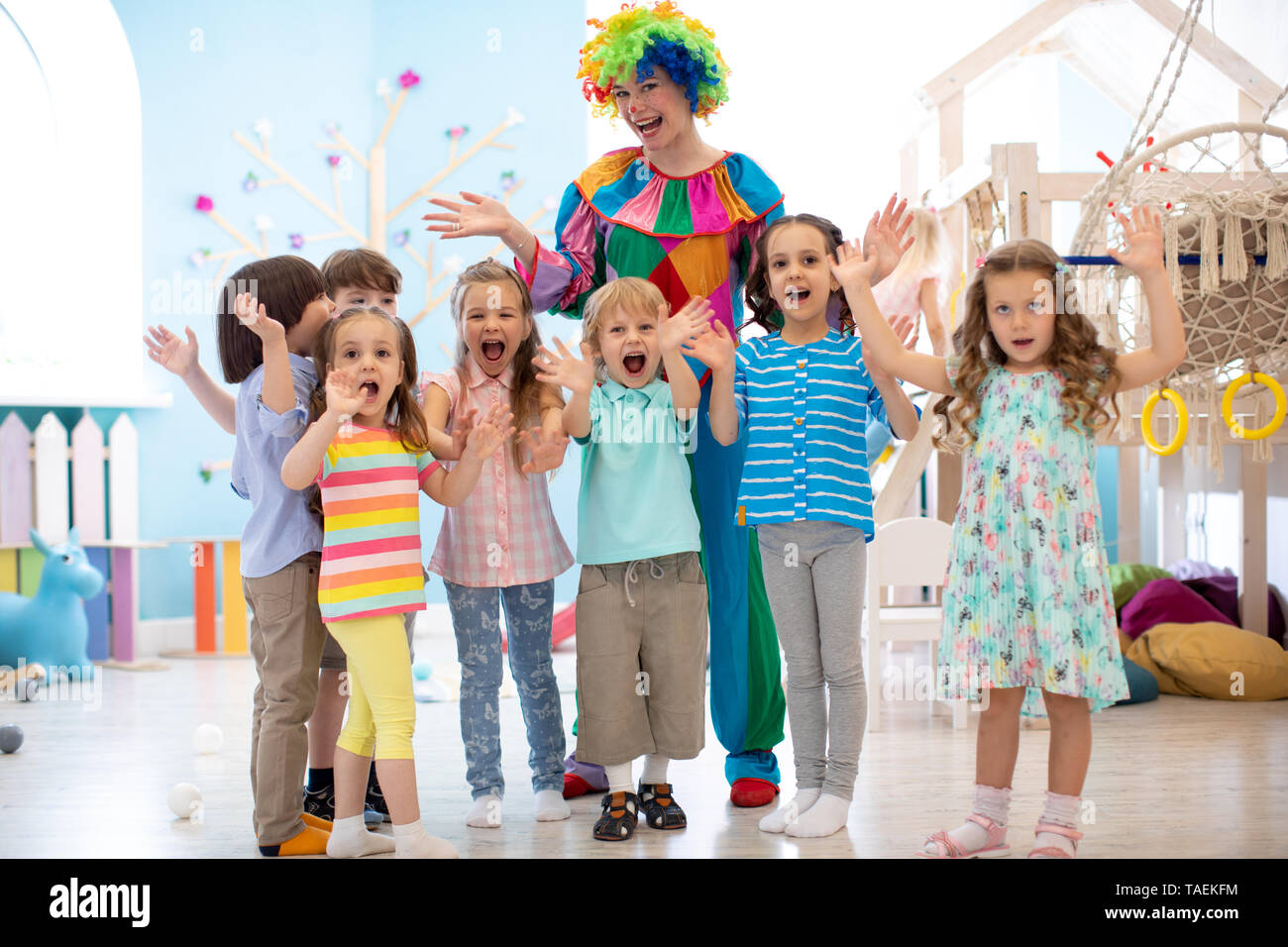 happy children group with clown celebrating birthday party in daycare ...