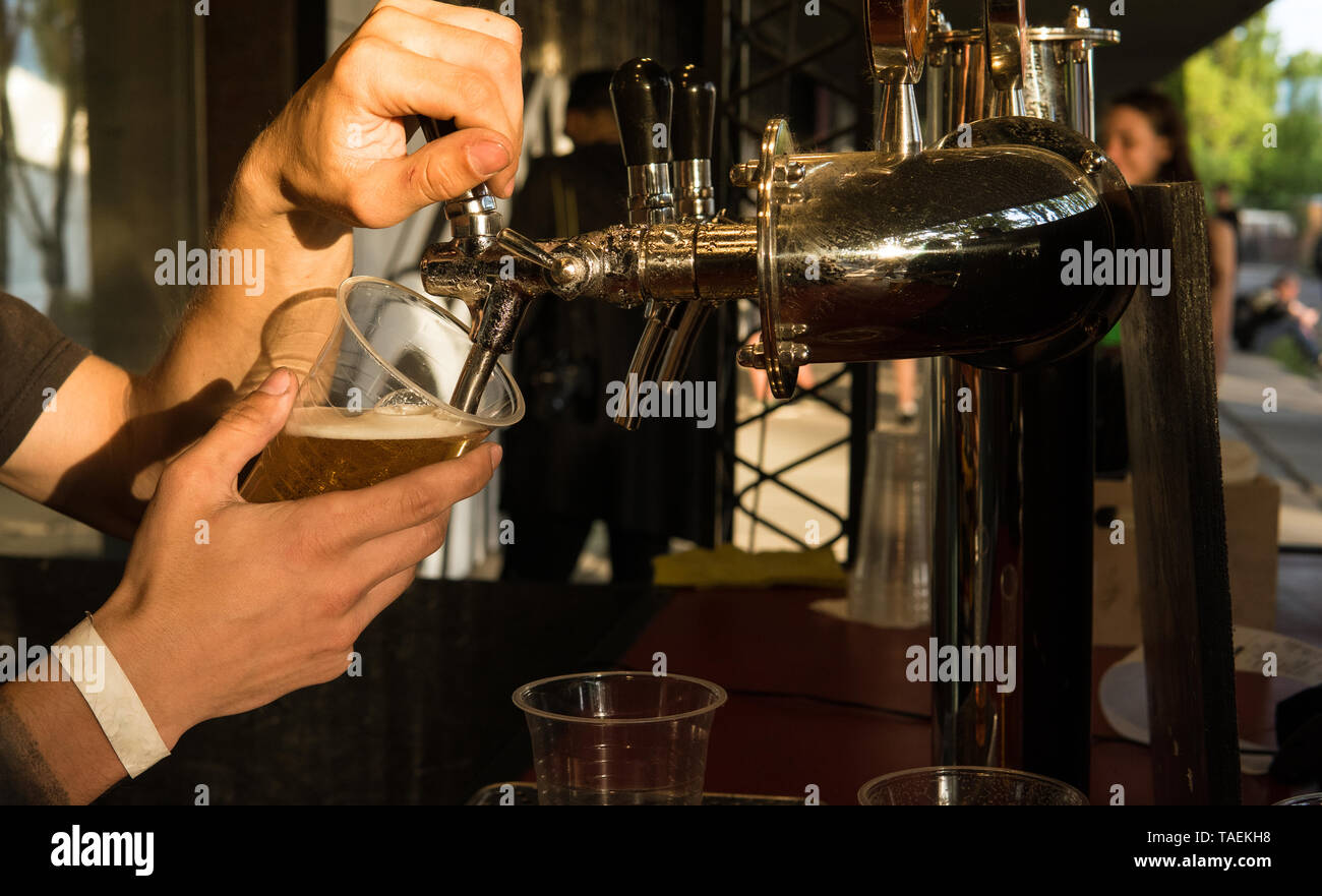 The male bartender pouring beer into a glass close-up. Street food. A glass with cold beer in ...