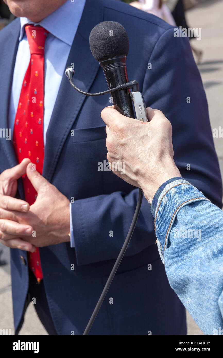 Journalist holding microphone, making media interview with a ...