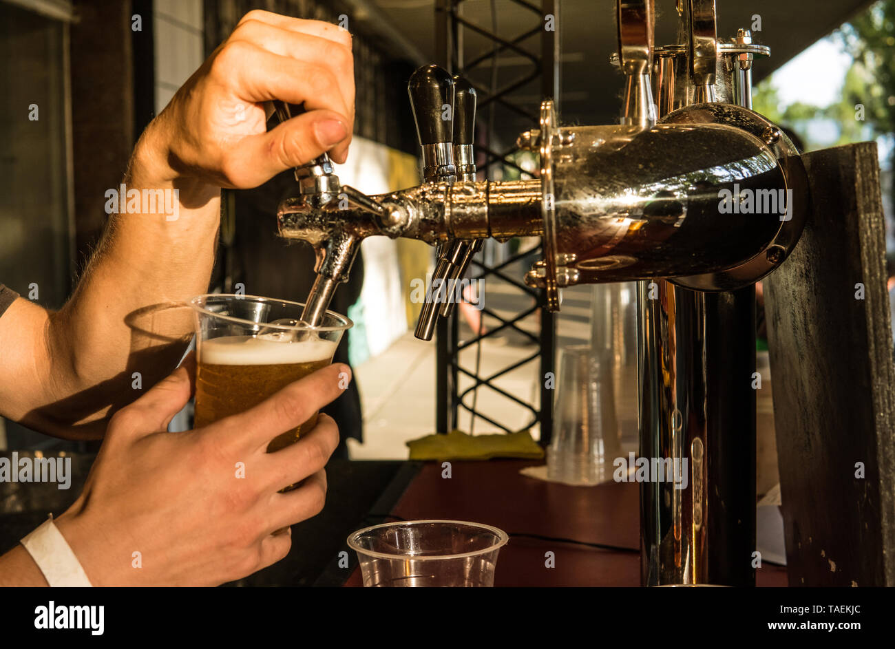 The male bartender pouring beer into a glass close-up. Street food. A glass with cold beer in ...