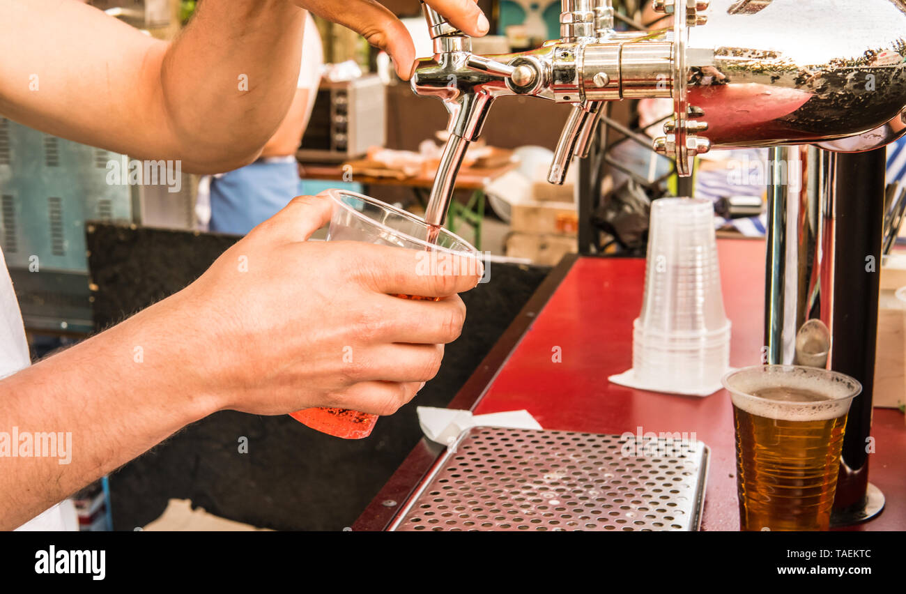 The male bartender pouring beer into a glass close-up. Street food. A glass with cold beer in ...