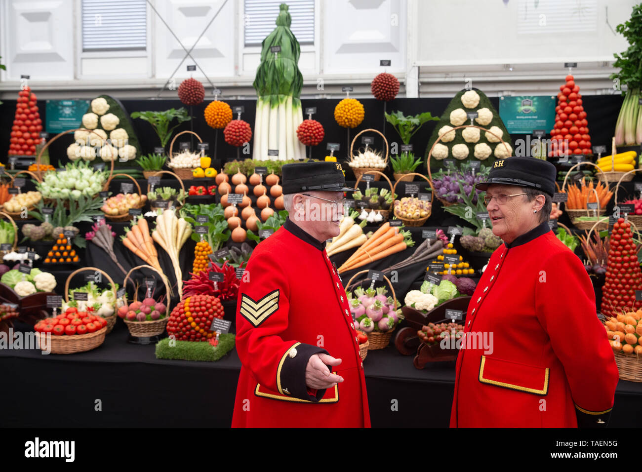 Two Chelsea Pensioners chatting in front of a colourful vegetable ...
