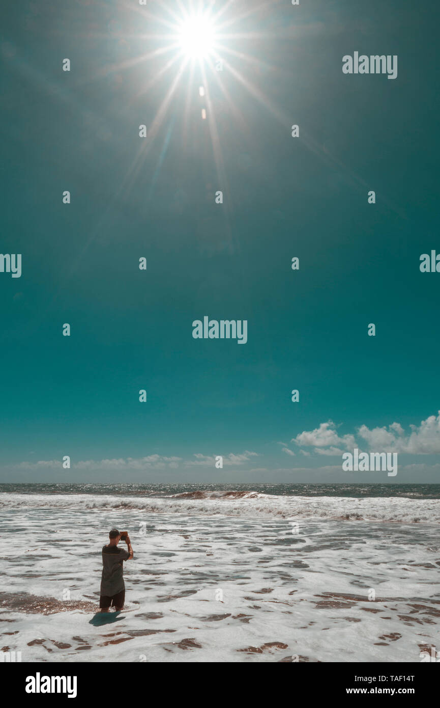 Spain, Canary Islands, Gran Canaria, man standing in water, taking ...