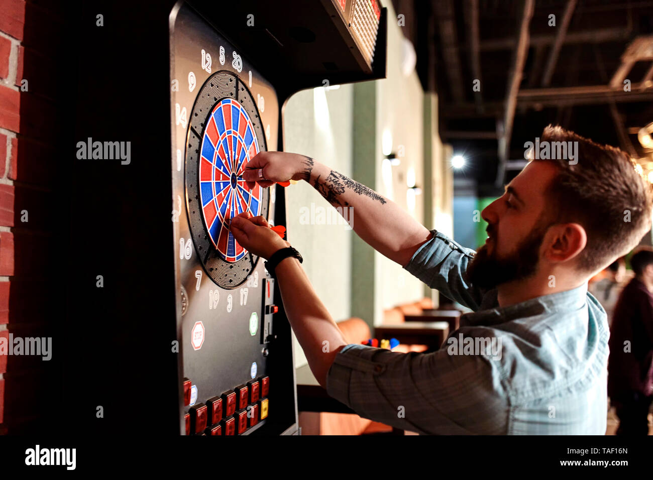 Man taking out darts from electronic dartboard Stock Photo - Alamy