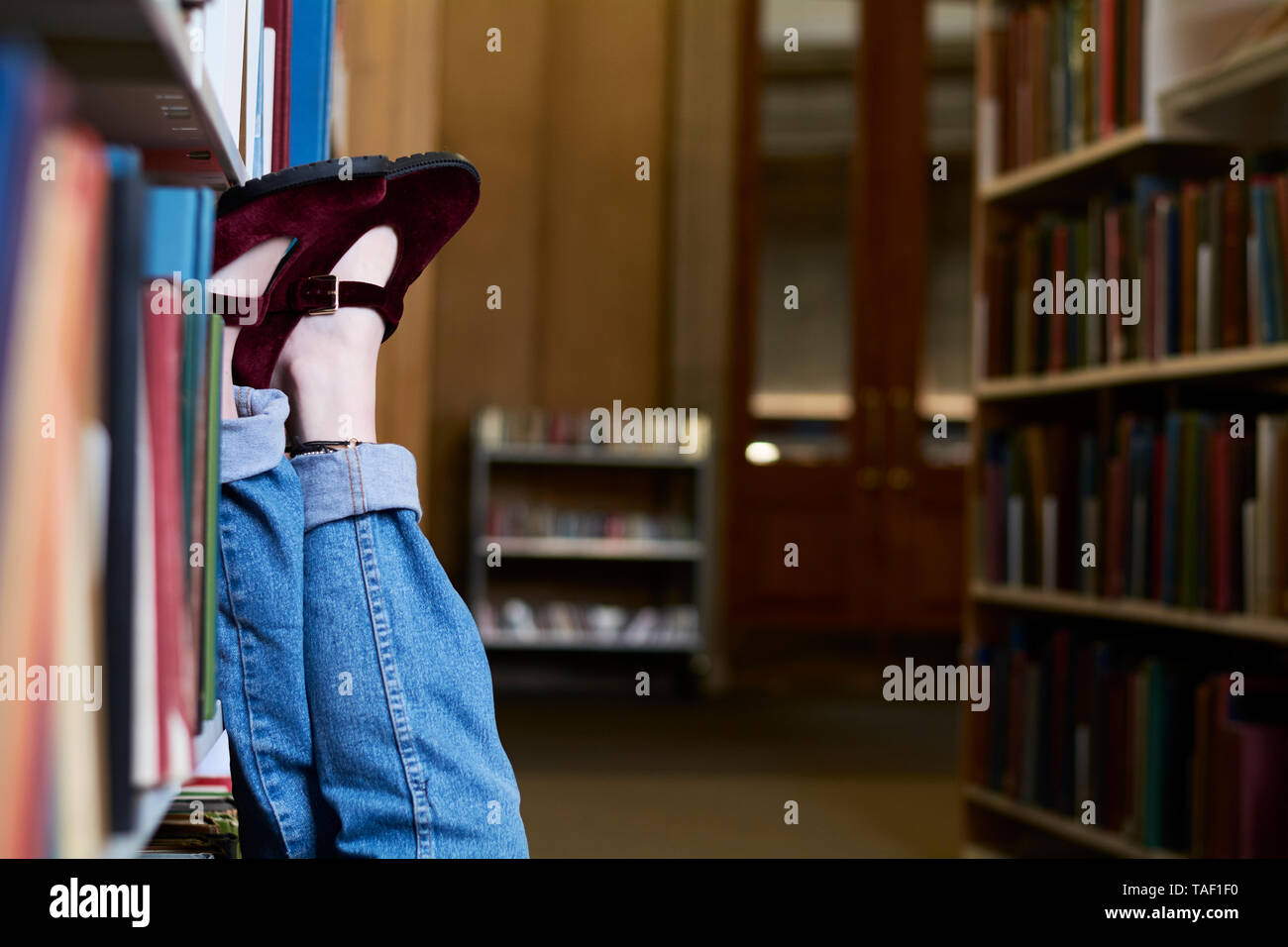 Female student in a public library, feet up Stock Photo - Alamy