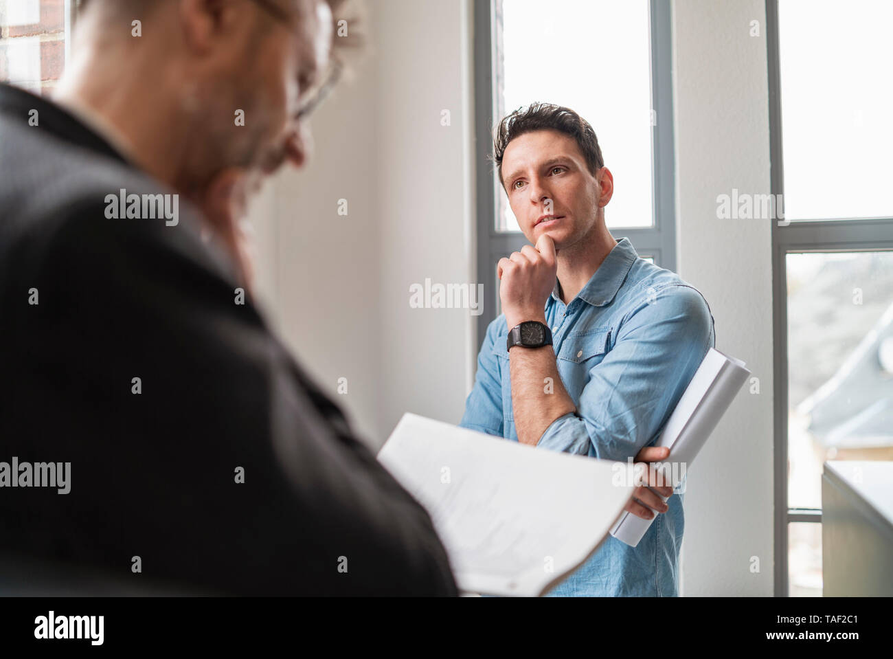 Two colleagues talking at the window in office Stock Photo - Alamy