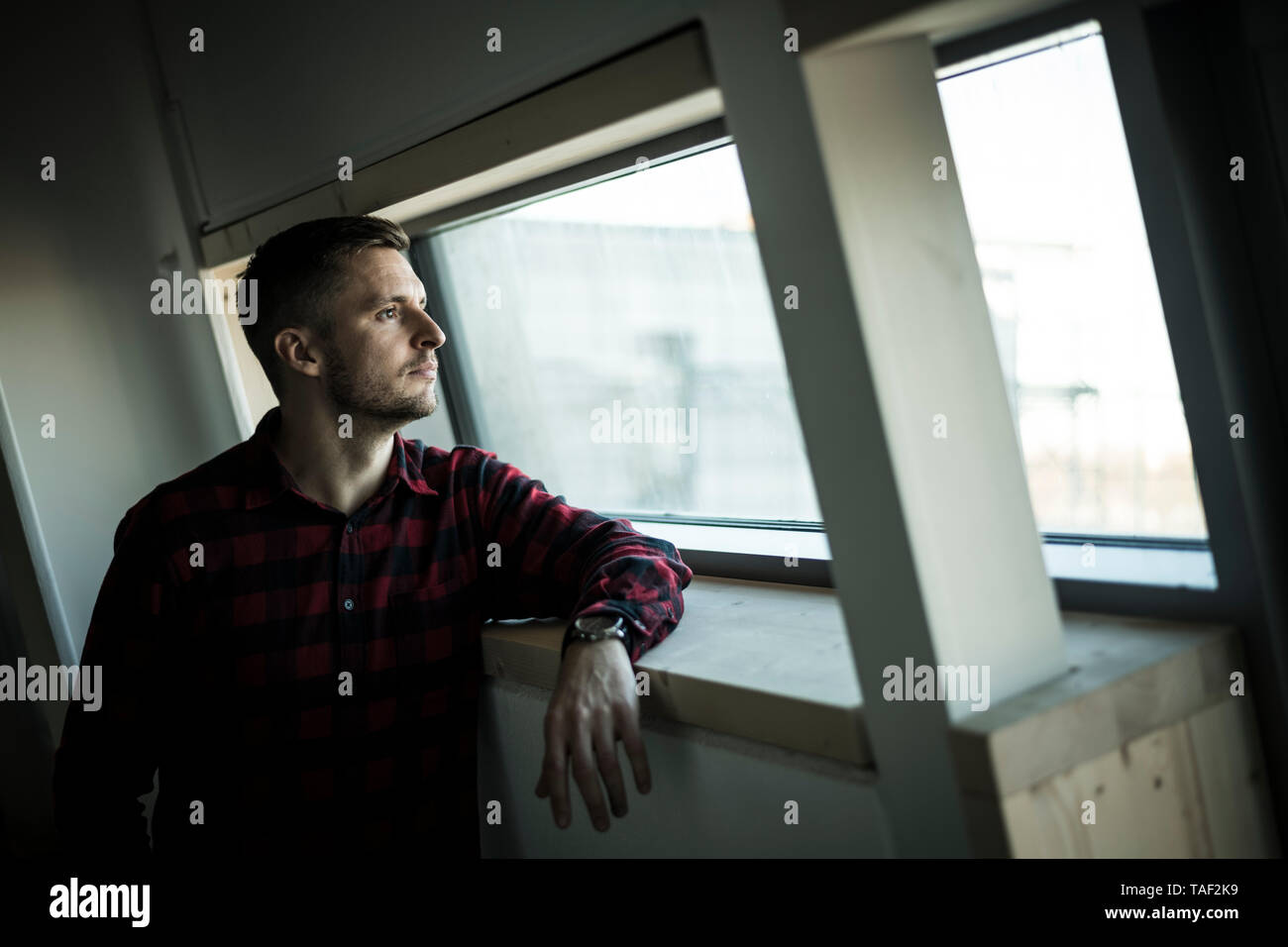 Young man looking out of window, daydreaming Stock Photo - Alamy