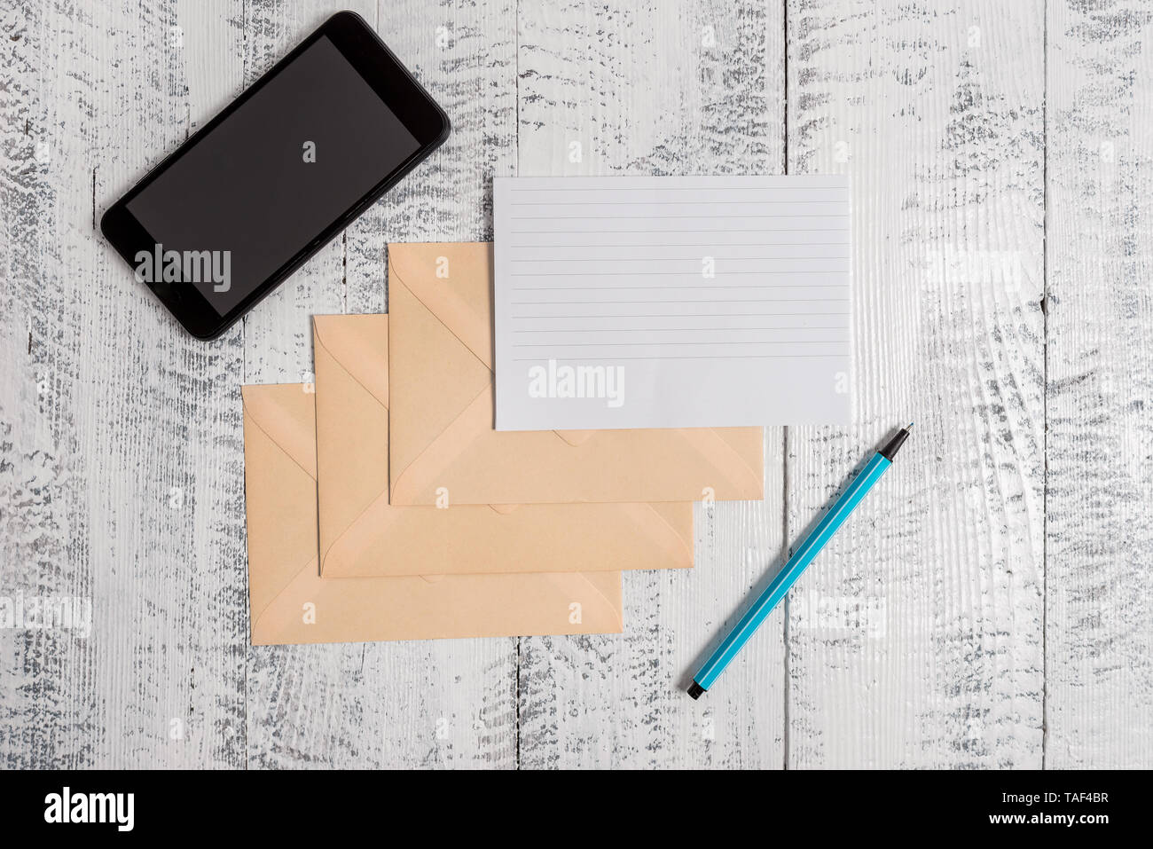 Three envelopes marker ruled paper smartphone sheet wooden background ...