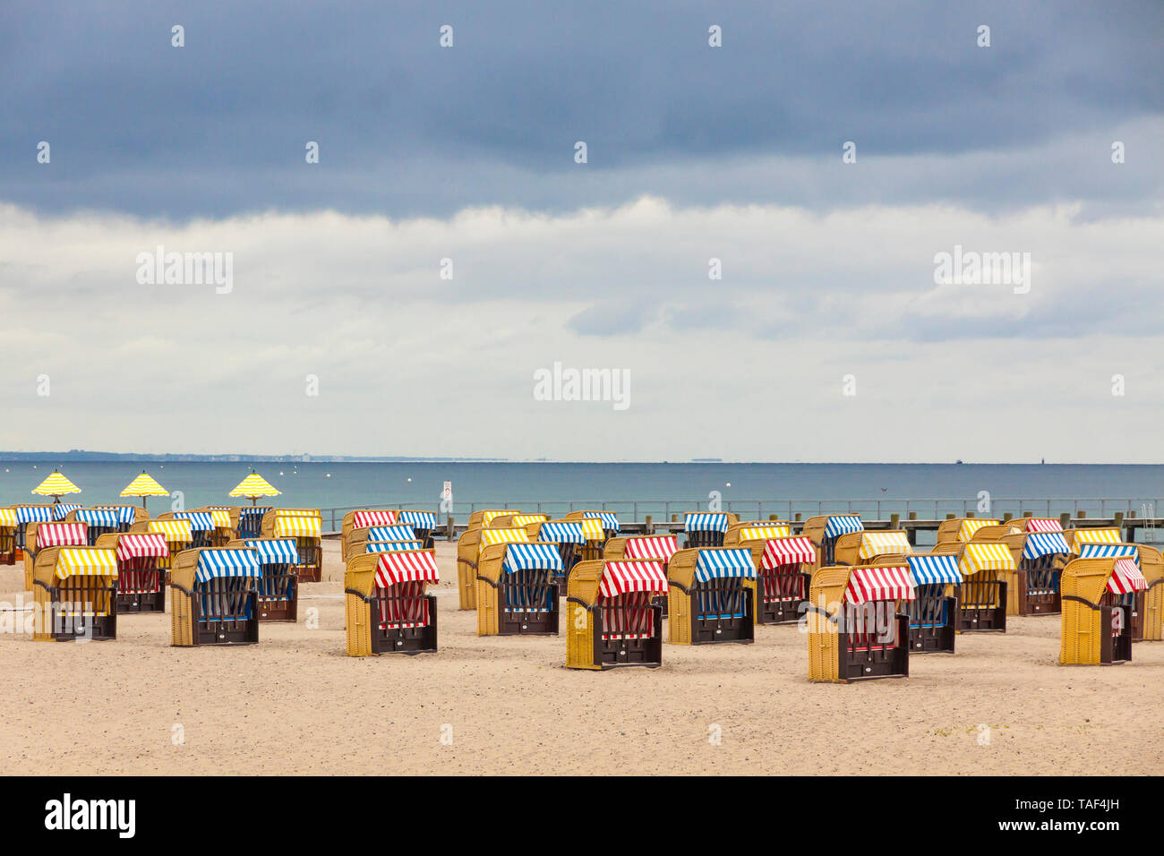 Colorful striped wooden hooded beach chairs (strandkorb) on a sandy ...