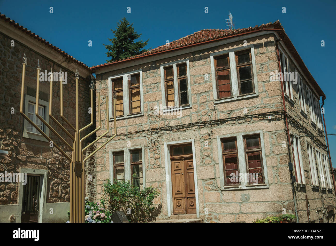 Old two-story house behind a metal sculpture in menorah shape at ...