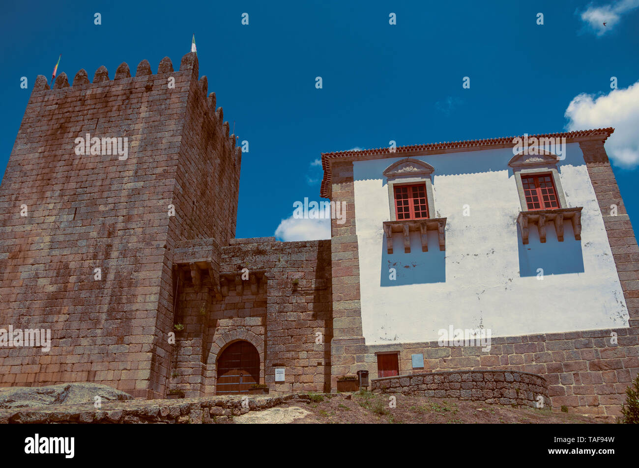 Stone walls and square tower over rocky hill, at the front facade of ...