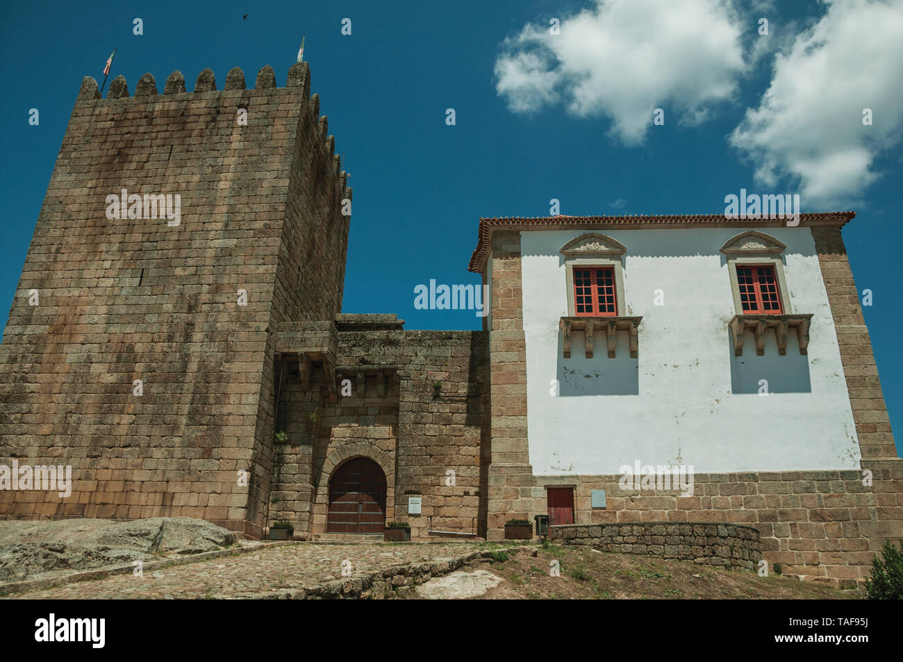 Stone walls and square tower over rocky hill on the facade of medieval ...