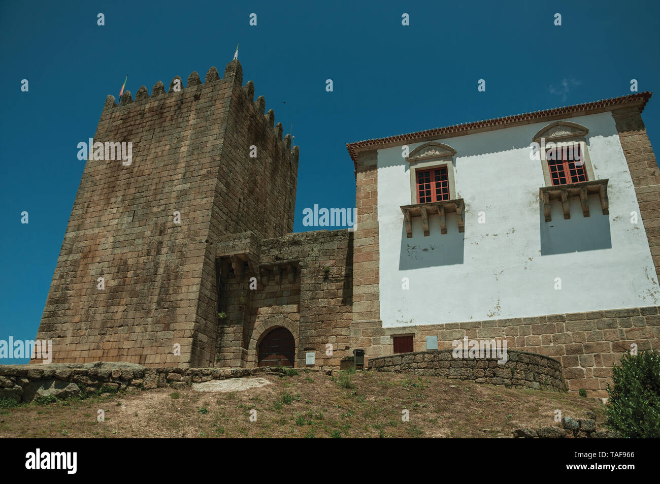 Stone walls and square tower over rocky hill on the facade of medieval ...