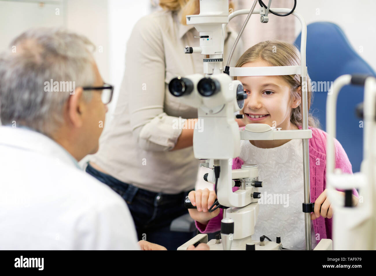 Mature male doctor look with eye apparatus in child’s eye at clinic ...