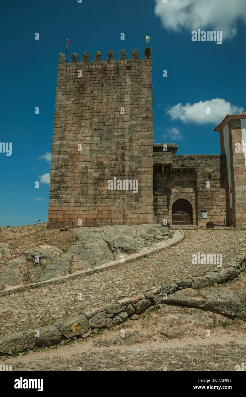Stone walls and square tower over rocky hill on the facade of medieval ...