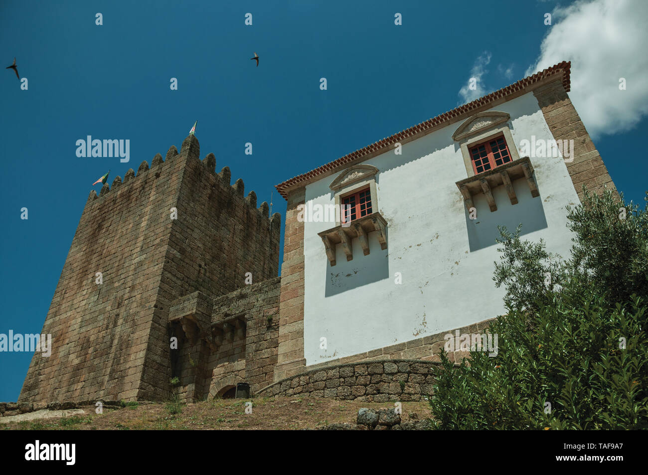 Stone walls and square tower over rocky hill on the facade of medieval ...