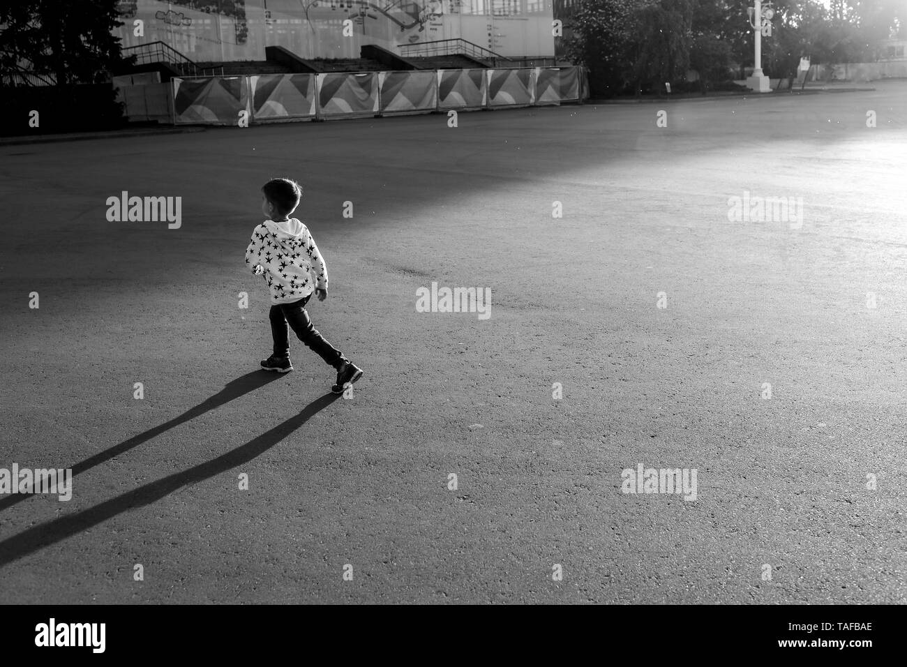 a little boy is walking on the road at sunset, casting a shadow Stock ...